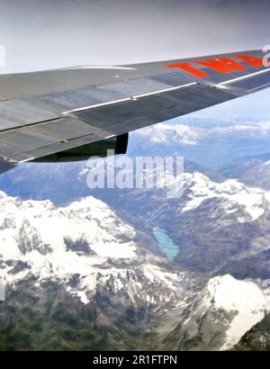 View of a wing of a TWA plane as it flies over the Alps ca. 1968 Stock ...