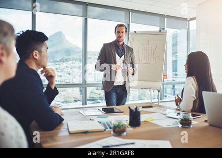 Guiding his team to success. a mature businessman giving a presentation ...