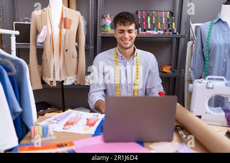 Young latin man tailor using laptop at atelier Stock Photo - Alamy