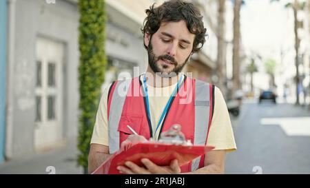 Young hispanic man having survey interview writing on clipboard at ...