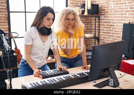 Two women musicians composing song using keyboard at music studio Stock ...