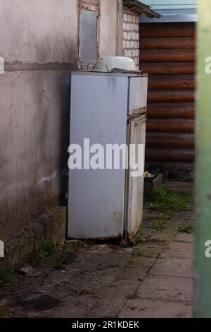 An old rusty refrigerator was thrown away on the street in sun light ...
