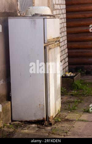 An old rusty refrigerator was thrown away on the street in sun light ...