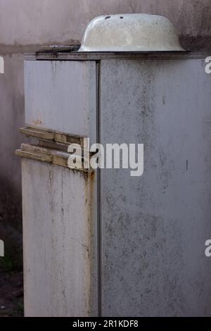 An old rusty refrigerator was thrown away on the street in sun light ...