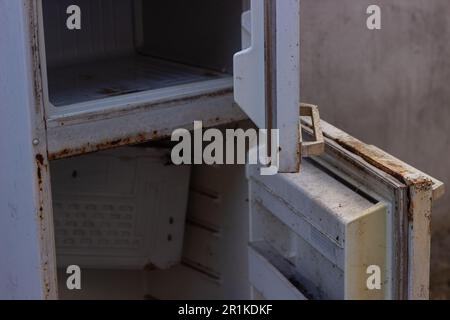 An old rusty refrigerator was thrown away on the street in sun light ...