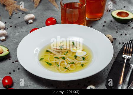 Low-fat chicken broth with a half cooked egg and parsley in a glass ...
