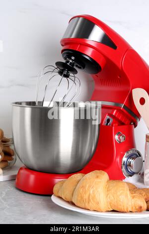 Modern red stand mixer, croissant and ingredients on gray marble table ...