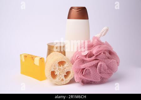 Pink shower puff, loofah sponge and cosmetic products on white ...