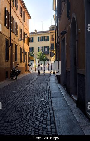 Very narrow cobbled street in the shade that makes a bend at the end in ...