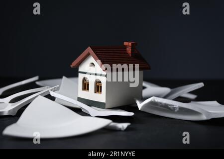 House model and broken dishes on black table depicting destruction ...