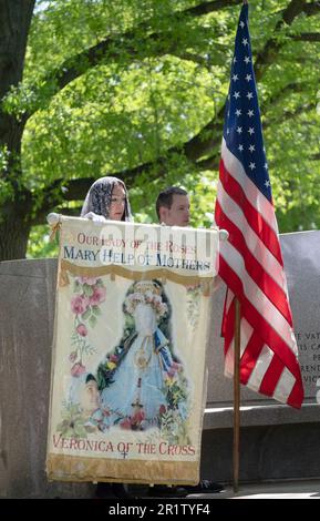 At a May Crowning ceremony, a devout Roman Catholic holds a banner with ...