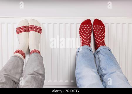 People warming feet near heating radiator, closeup Stock Photo - Alamy