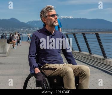 Concentrated disabled man in wheelchair working on spinal injury ...