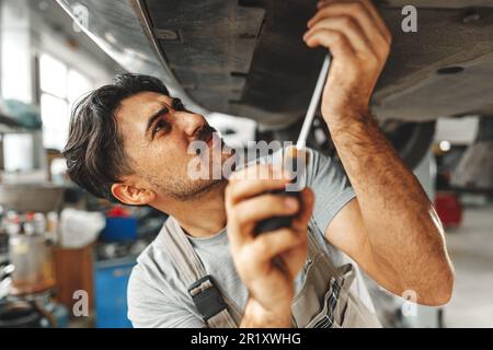 Workman mechanic working under car in auto repair shop Stock Photo - Alamy