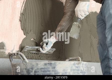 A closeup of a person applying cement on a brick with a spatula in a ...