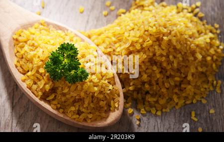 Composition with a bowl and spoon of uncooked bulgur on a table Stock ...