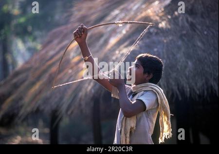 Jenu Kurumba tribal boy aiming with a stone, Nagarahole, Karnataka ...