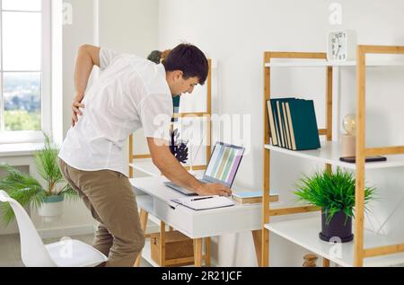 Young man gets tired and feels intense back pain after working at his ...