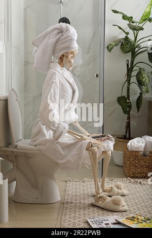 Skeleton in bathrobe with mobile phone sitting on toilet bowl Stock ...