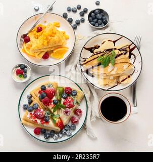 Variety of fresh crepes with chocolate, jam, fruits and berries on ...