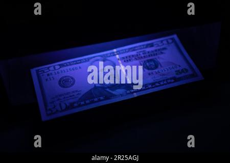 Close-up of dollars under an ultraviolet lamp. Inspection of a dollar ...