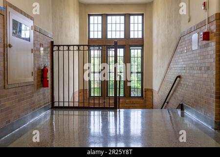 Nondescript stairway, hallway, with windows and brown railing, in a ...