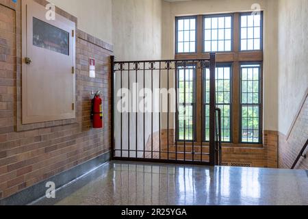 Nondescript stairway, hallway, with windows and brown railing, in a ...