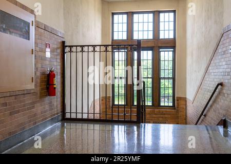 Nondescript stairway, hallway, with windows and brown railing, in a ...