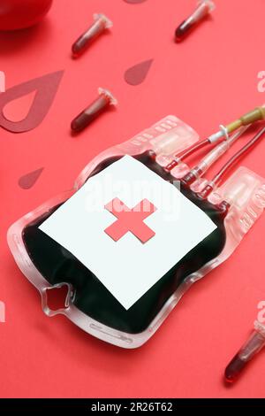 Blood pack with tubes and paper drops on red background, closeup. World ...
