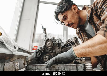 Workman disassembling car engine at the working table of the car ...