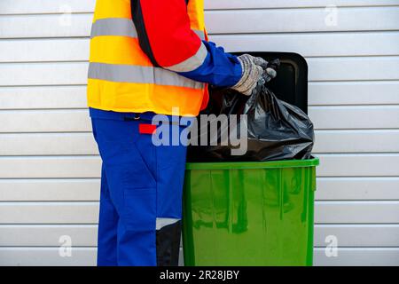 Janitor takes garbage out of trash container outdoors Stock Photo - Alamy