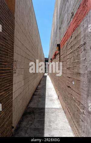 Narrow passage between white painted rendered buildings with person ...