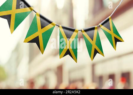 A garland of Jamaica national flags on an abstract blurred background ...