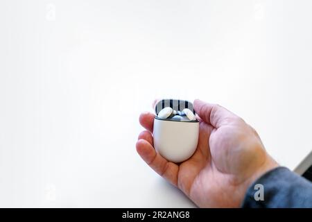 White earbuds in open case. Case rests on plain gray surface ...