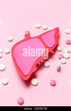 Paper liver with pills on pink background Stock Photo - Alamy