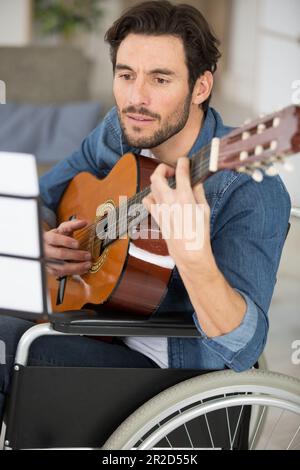musician in wheelchair playing guitar at home Stock Photo - Alamy
