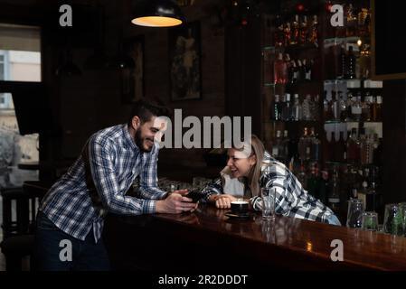 Young colleagues bartenders and waitress sit at the bar and get bored ...