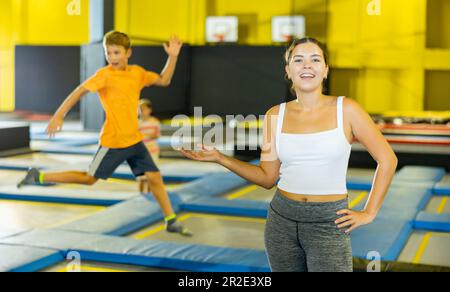Woman trampolining coach against the background of children playing and ...
