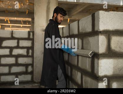 A worker may be seen using a level to inspect a brick wall Stock Photo ...