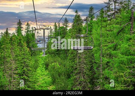 Tourist double lift above the forest on the mountain slope Stock Photo ...