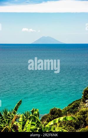 Distant Stromboli volcano with blue sea and sky on a hazy sunny day ...