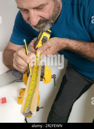 Front view of a bearded carpenter measuring a timber with a tape ...