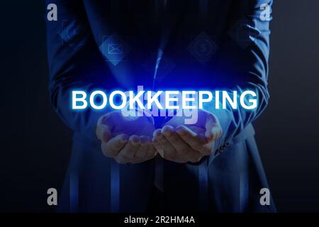 Bookkeeping concept. Businessman holding word on dark blue background ...