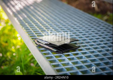 Black wallet on metal bench outdoors. Lost and found Stock Photo - Alamy
