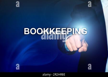 Bookkeeping concept. Businessman pointing at word on dark blue ...