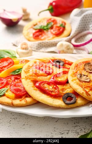 Plate with different tasty mini pizzas and ingredients on white ...