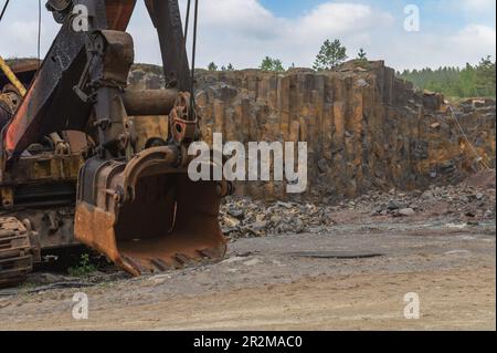 Basalt mining. Excavators in a basalt quarry near the forest. Large ...
