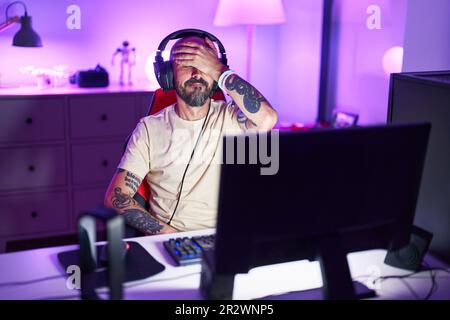 Young bald man streamer playing video game using computer at gaming ...