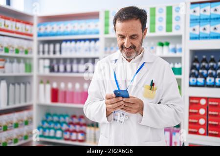 Middle age man pharmacist using smartphone working at pharmacy Stock ...