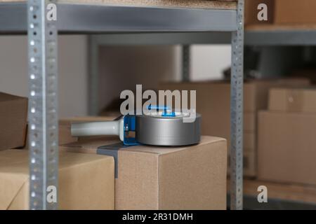 Adhesive tape dispenser on cardboard box indoors Stock Photo - Alamy